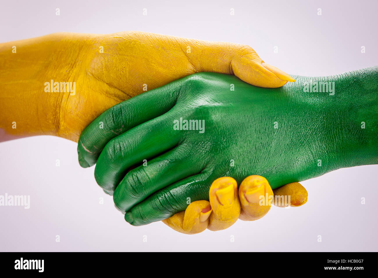 Yellow and green hands shaking together Stock Photo - Alamy