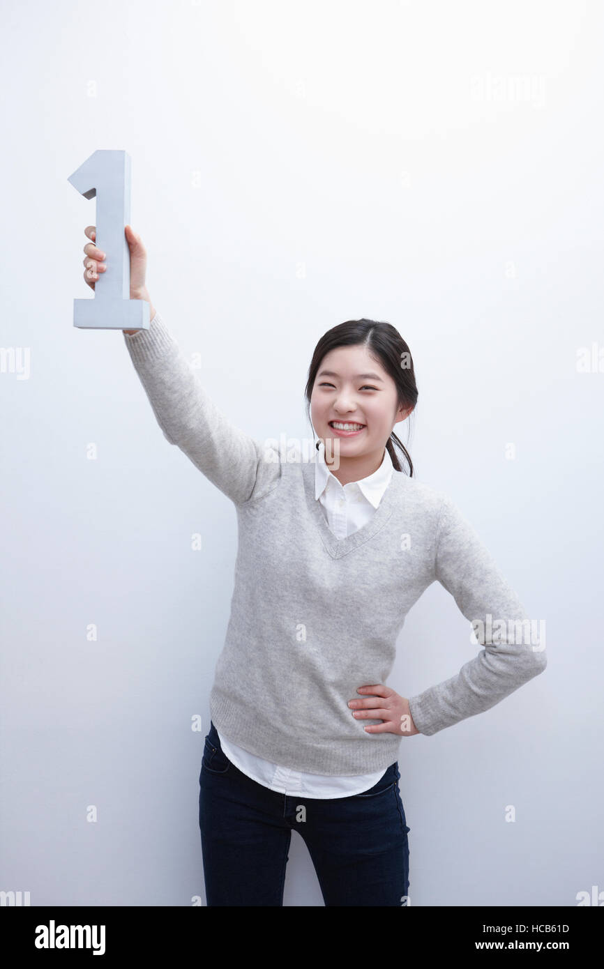 Smiling middle school girl holding up number one Stock Photo - Alamy