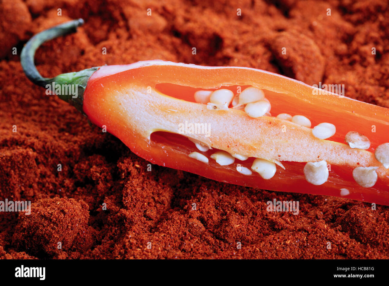 Red peperoni cut in half (Capsicum) on chili powder Stock Photo - Alamy