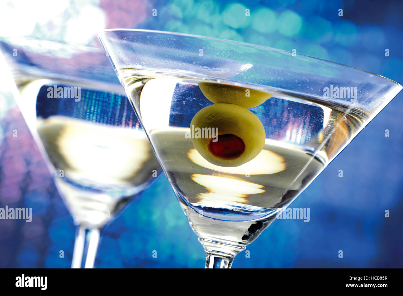 Two Martinis in cocktail glasses with a green olive Stock Photo - Alamy