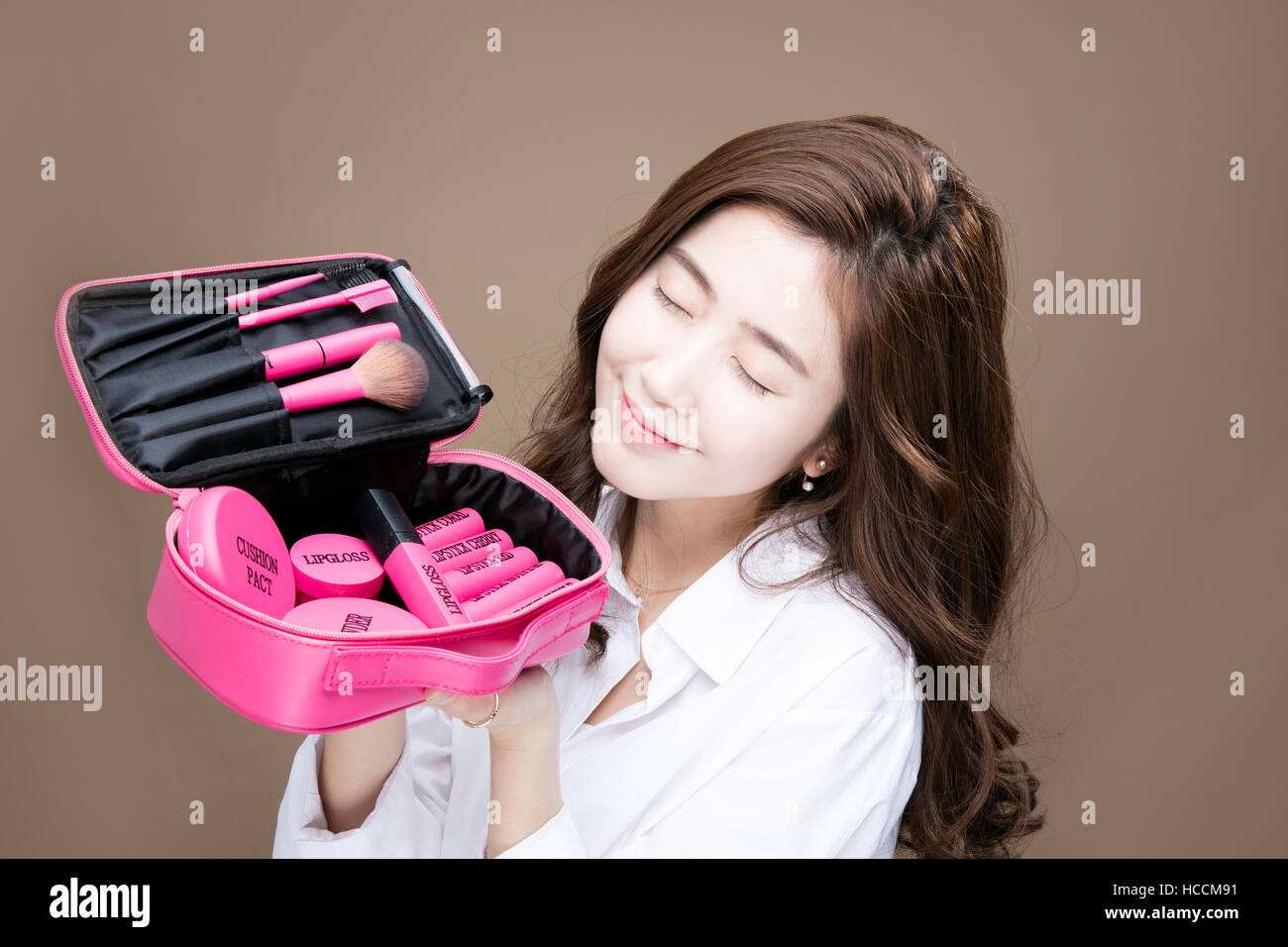 Portrait of young smiling woman with makeup pouch Stock Photo - Alamy