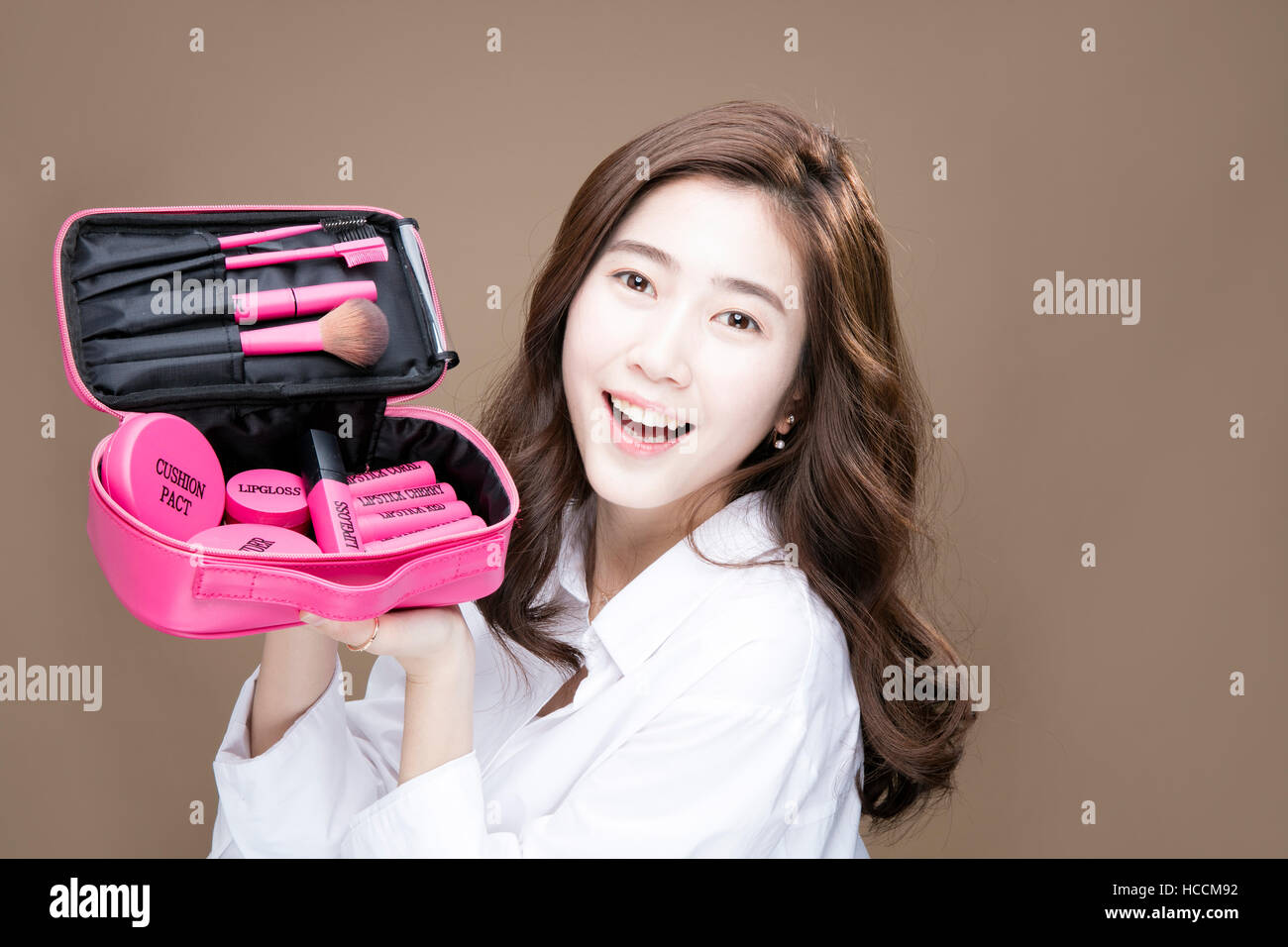 Portrait of young smiling woman with makeup pouch Stock Photo - Alamy