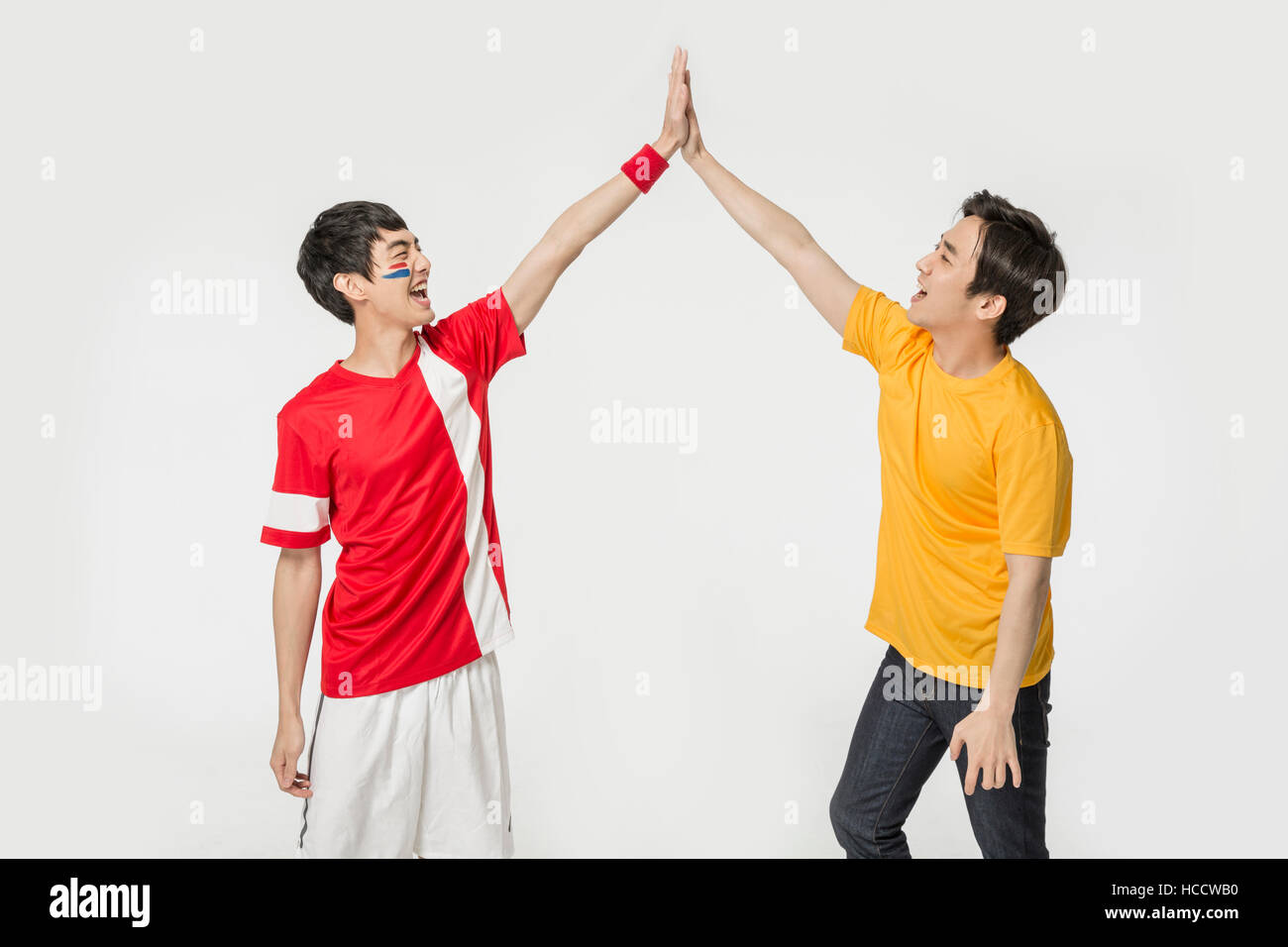 Side view of young smiling men slapping high fives Stock Photo - Alamy