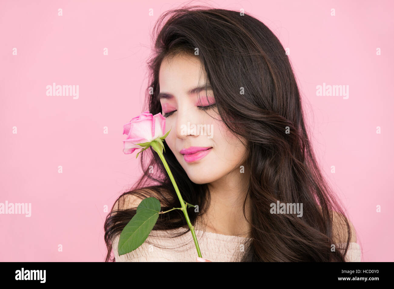 Portrait of young woman with pink rose closing eyes Stock Photo - Alamy