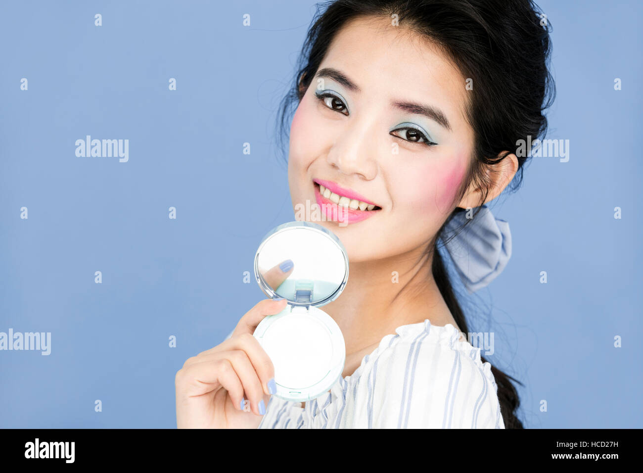 Portrait of young woman with powder compact Stock Photo - Alamy