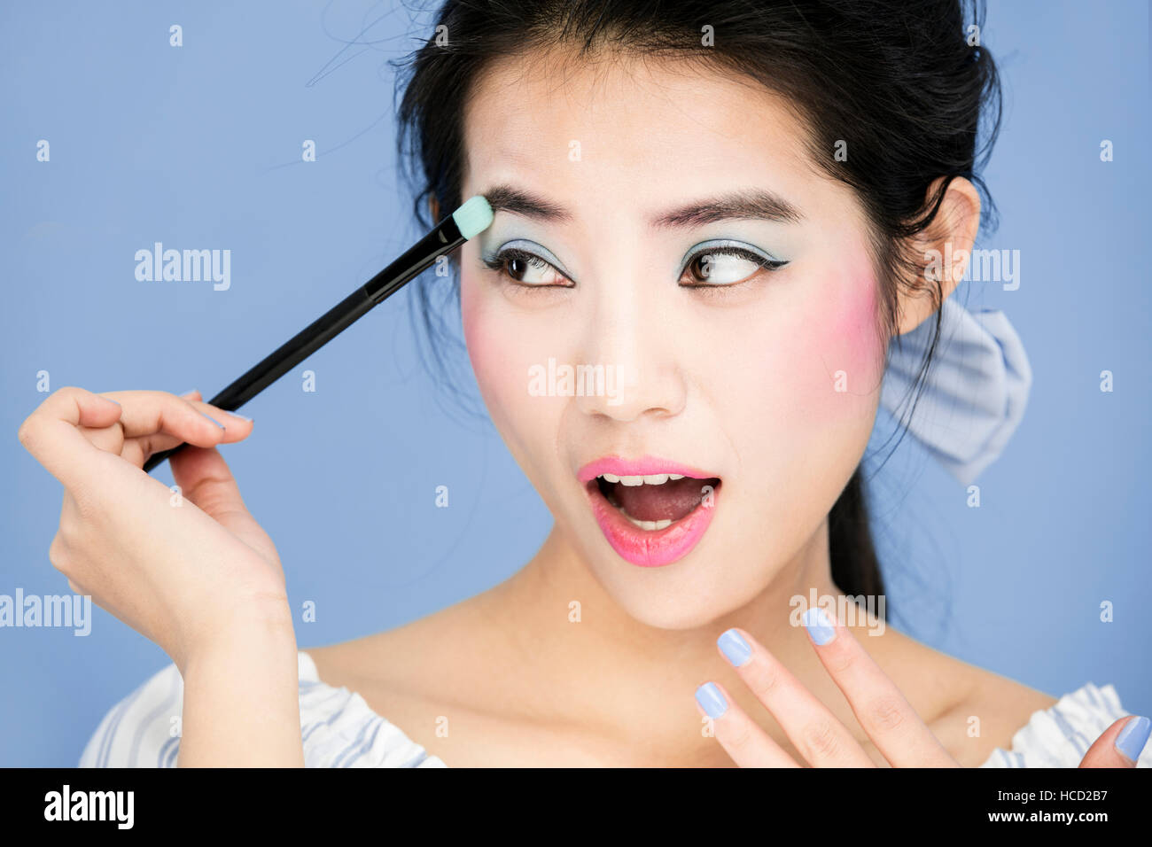 Portrait of young woman putting on eyeshadow Stock Photo - Alamy