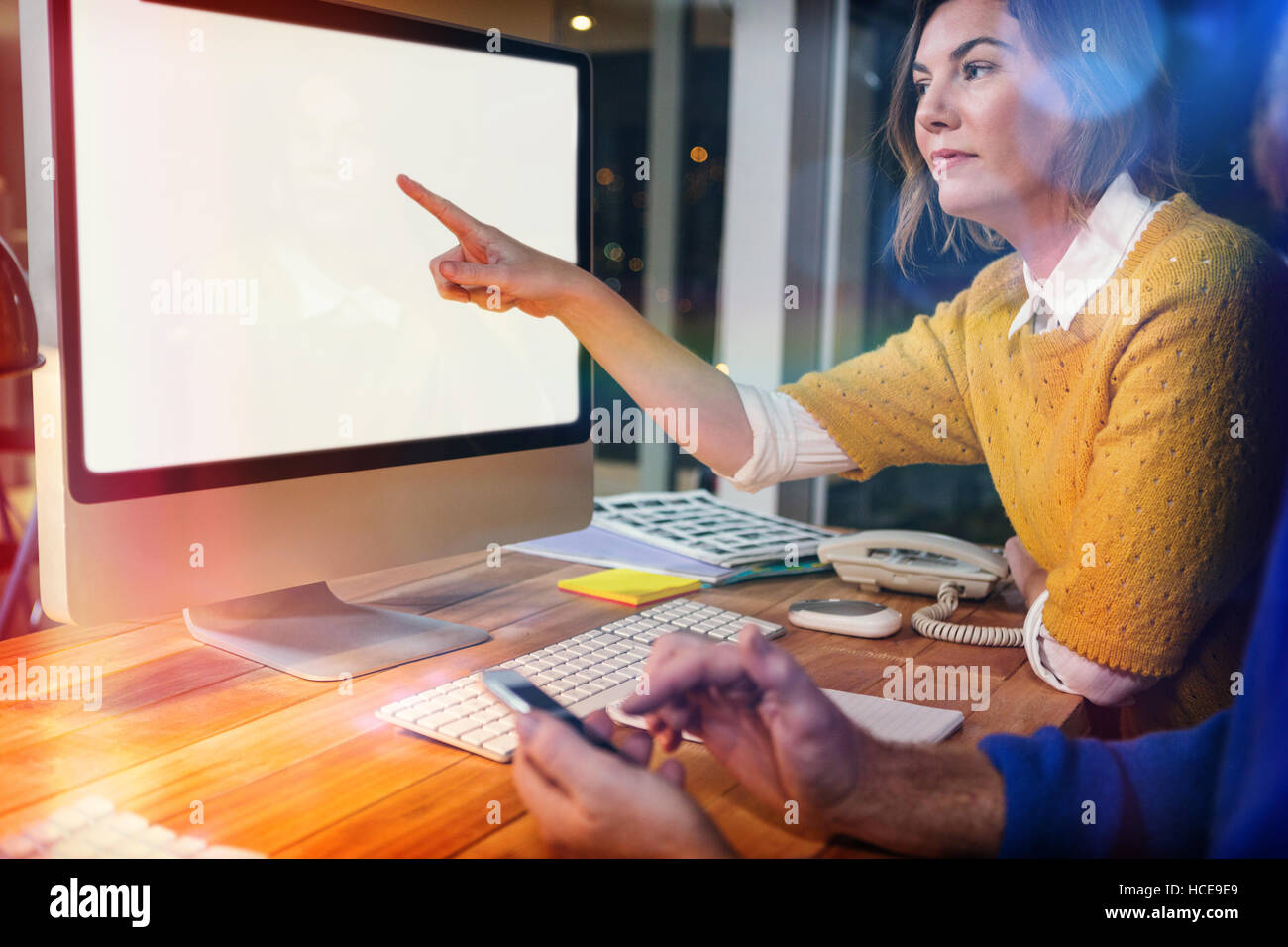 Businesswoman and colleague interacting while working on computer at ...