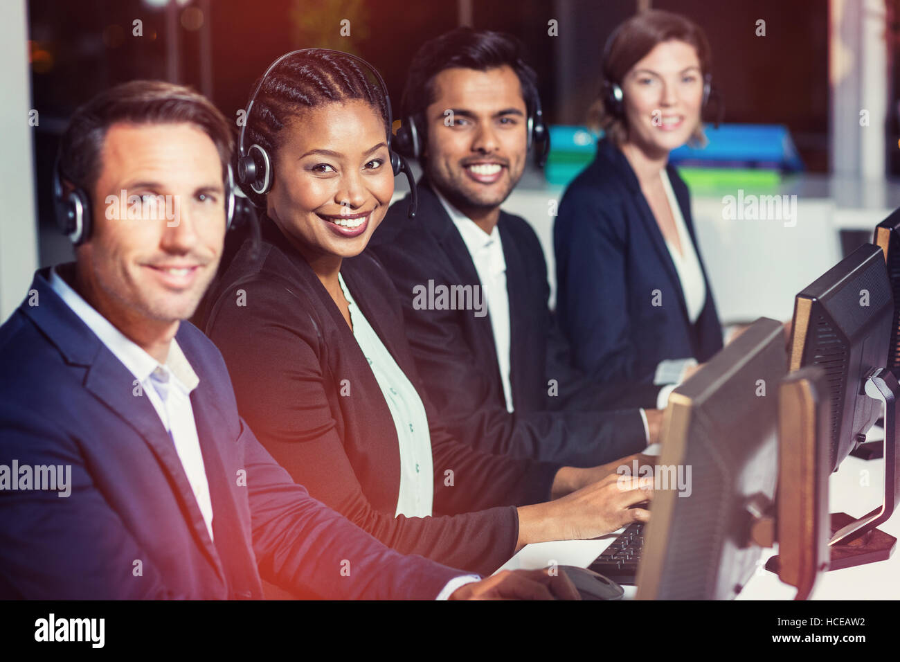 Colleagues with headsets using computer at office Stock Photo - Alamy