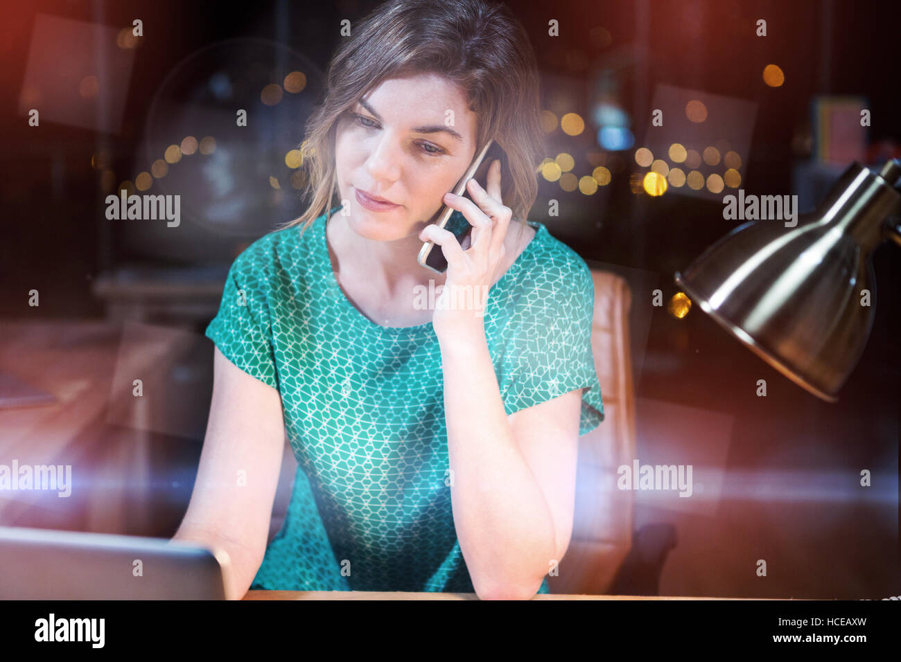 Businesswoman talking on mobile phone while working on laptop Stock ...