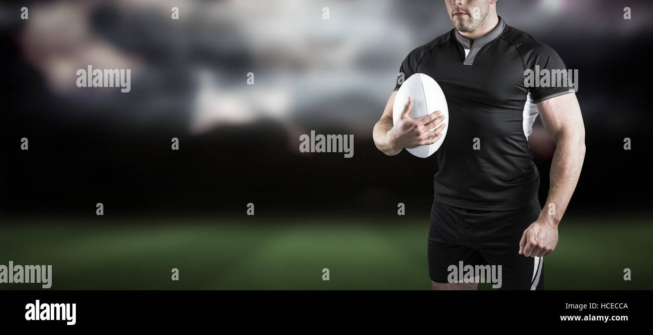 Composite image of tough rugby player holding ball Stock Photo - Alamy
