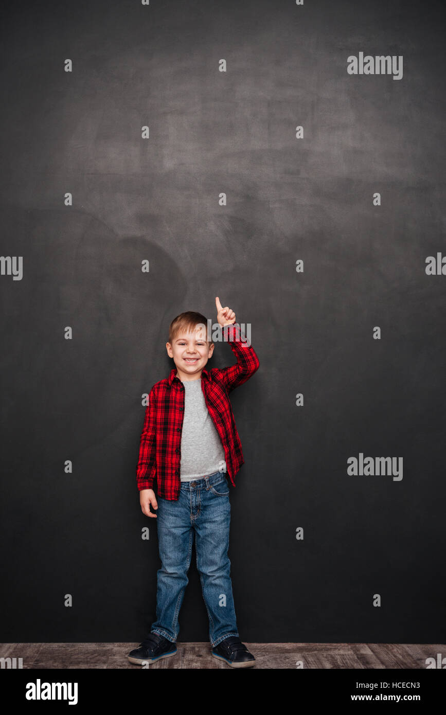 Image of happy little boy standing over chalkboard and pointing up ...