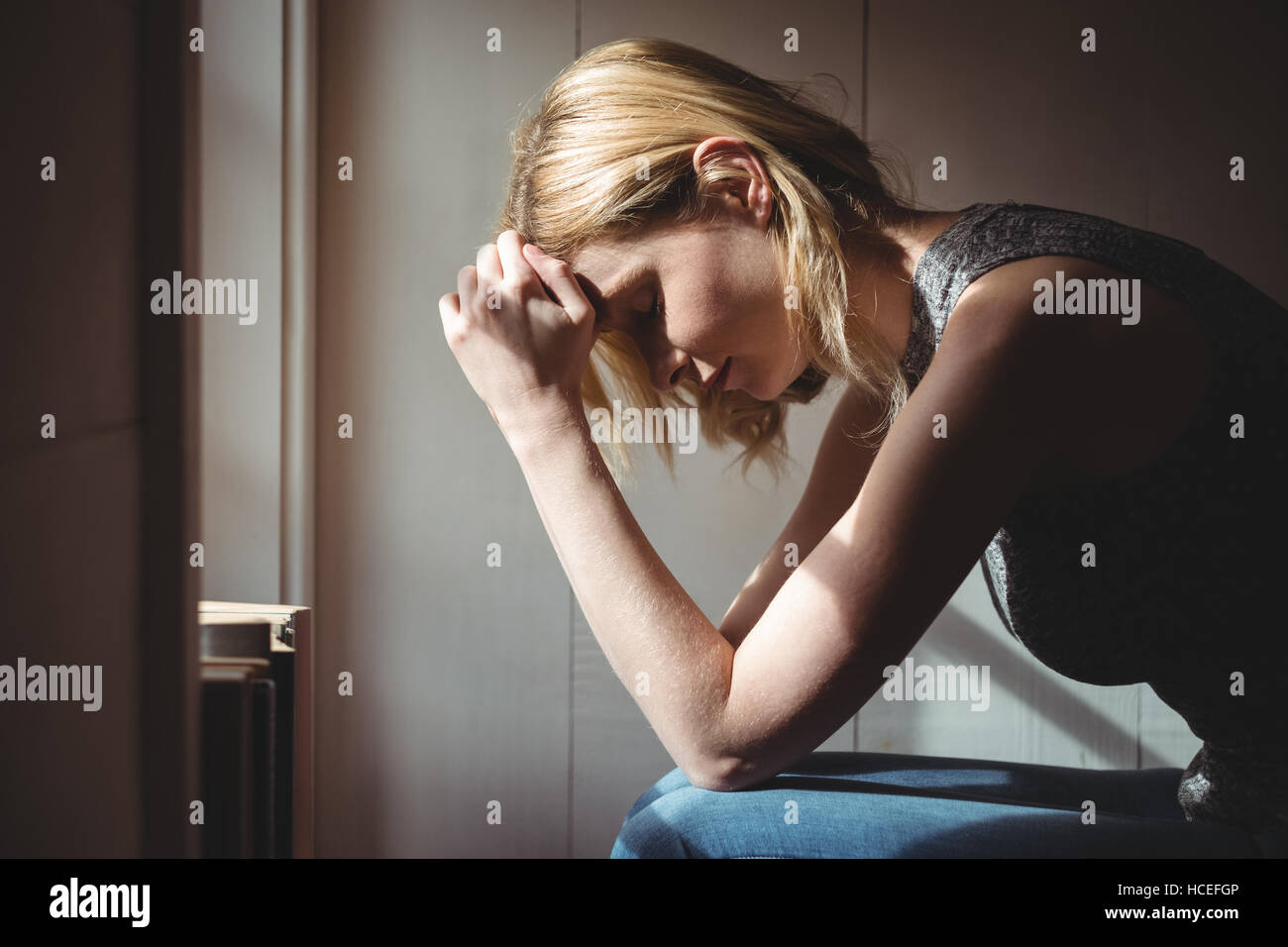 Tensed woman sitting with hand on forehead Stock Photo - Alamy