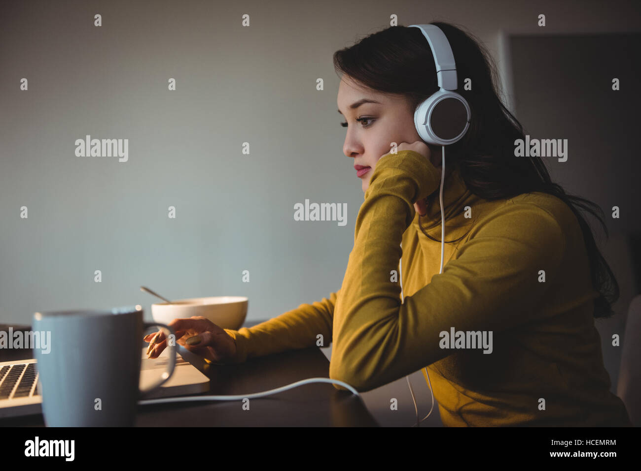Woman listening to headphones while using laptop Stock Photo - Alamy
