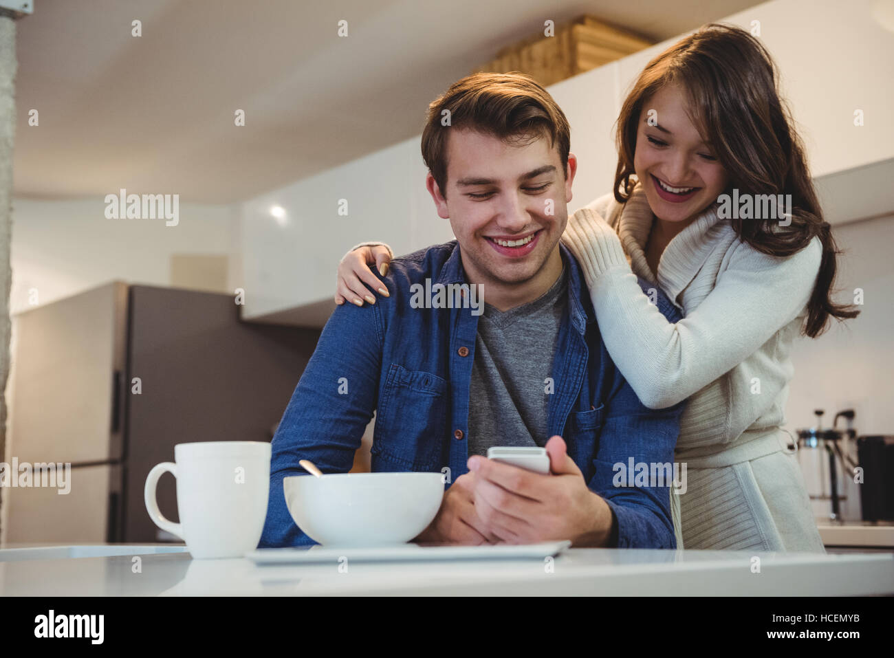 Couple using mobile phone while having breakfast Stock Photo - Alamy