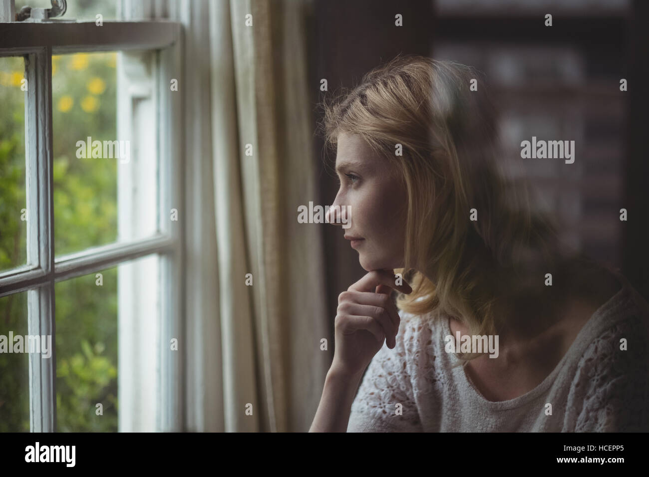 Beautiful woman looking through window Stock Photo - Alamy