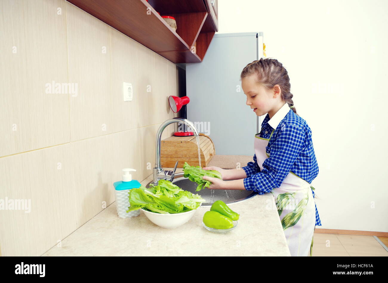 Little girl is washing vegetables for salad closeup Stock Photo - Alamy