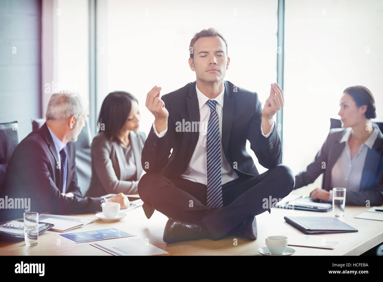 Businessman meditating in conference room Stock Photo - Alamy
