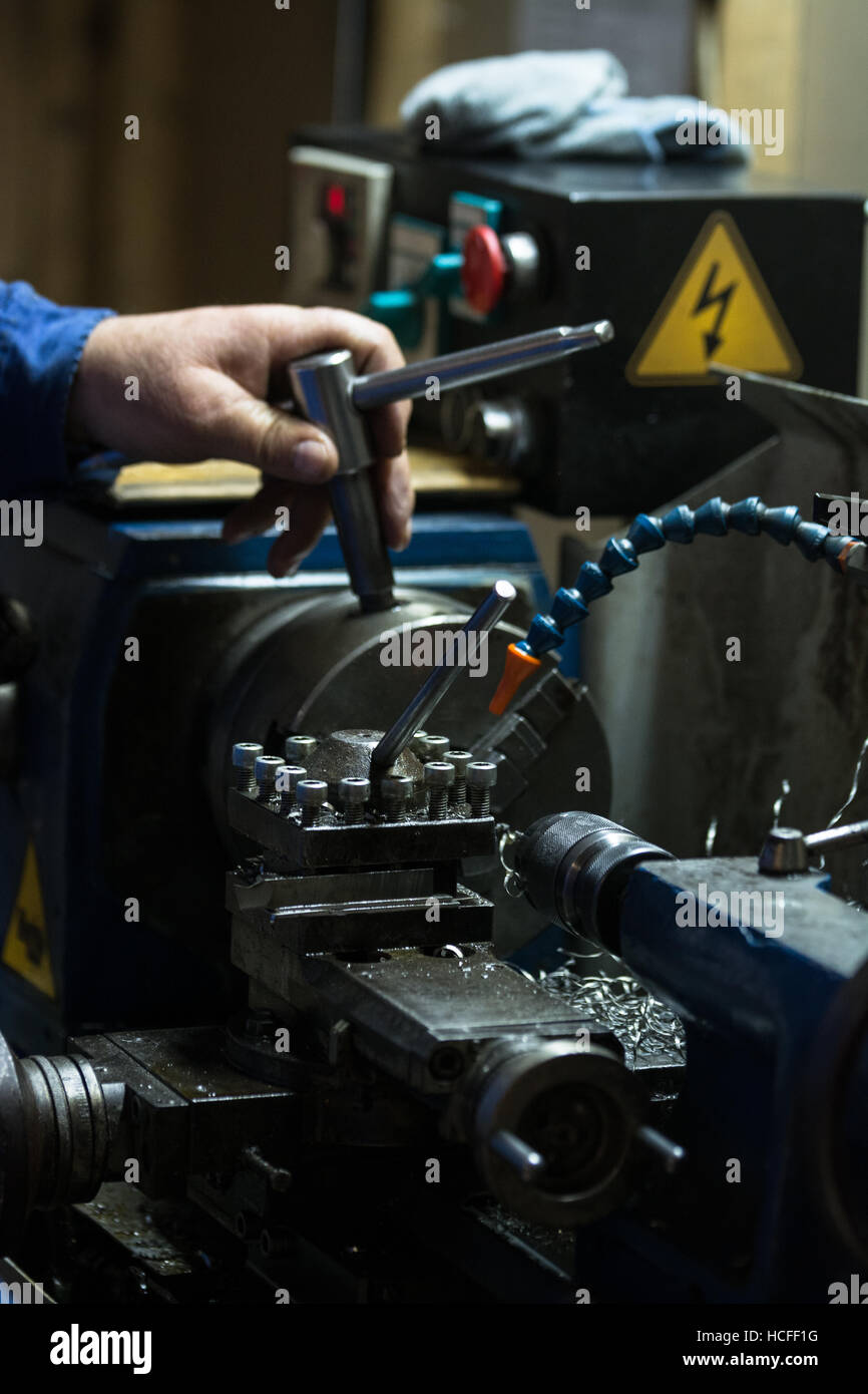 Metalworking. Man working on a small lathe machine in a craftsman ...