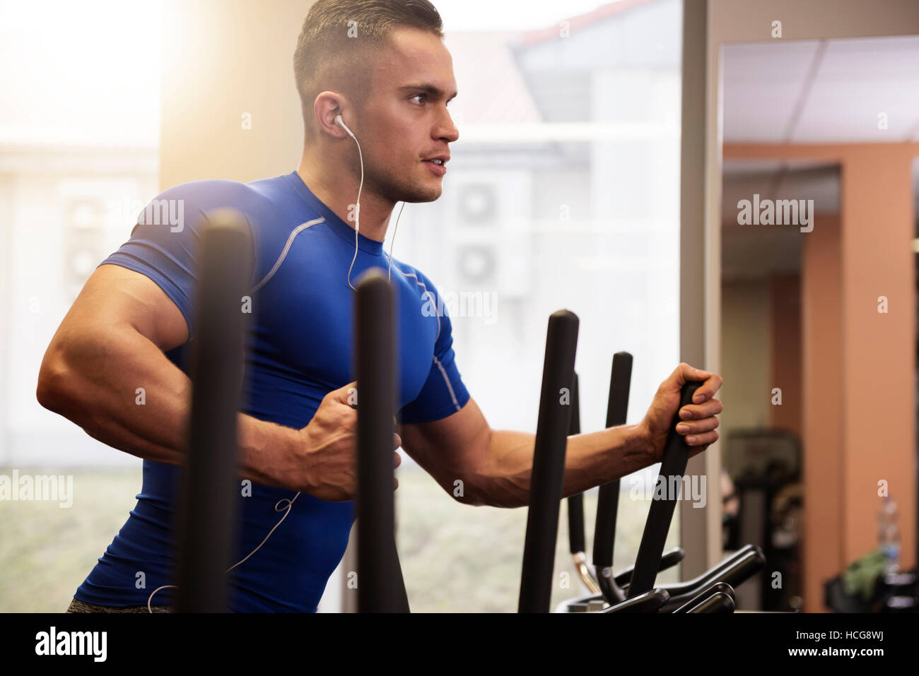 Handsome man on elliptical trainer Stock Photo - Alamy