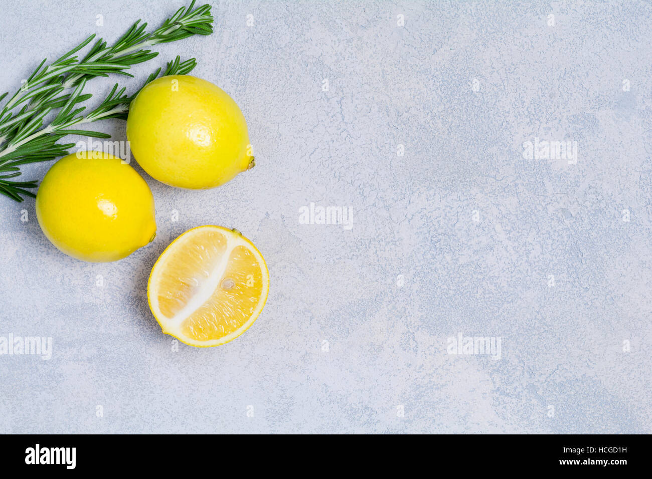 Fresh organic lemons and rosemary on bright blue stone background with ...