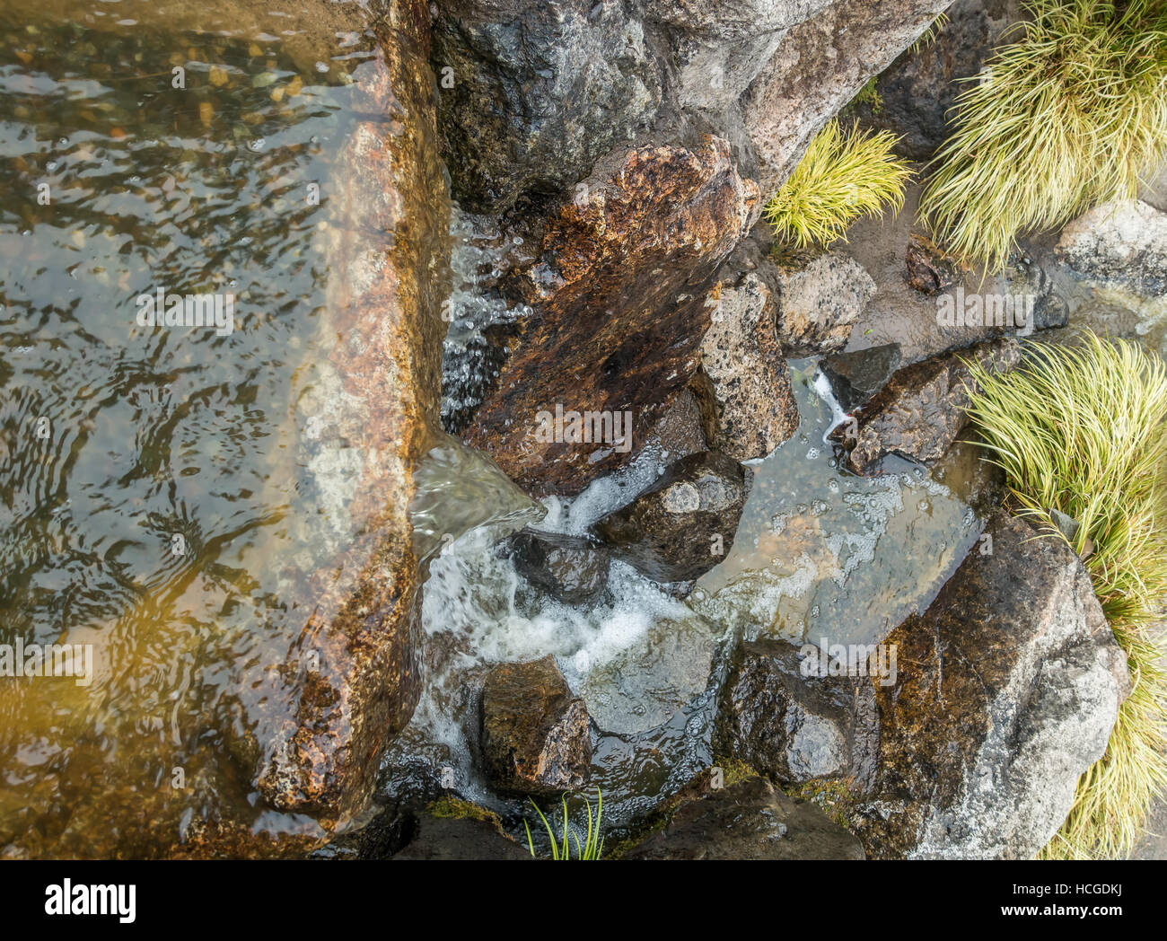 Water flows over a rock ledge creating a small waterfall somewhere in ...