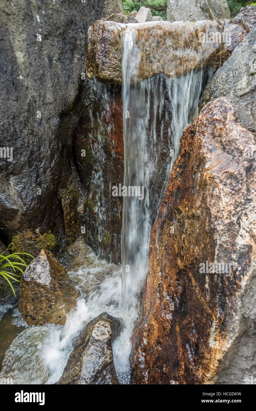 Water flows over a rock ledge creating a small waterfall somewhere in ...