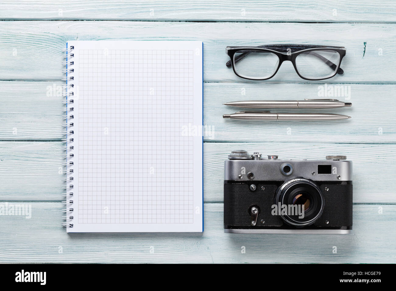 Office desk with photo camera, glasses, notepad, pen and pencil. Top ...