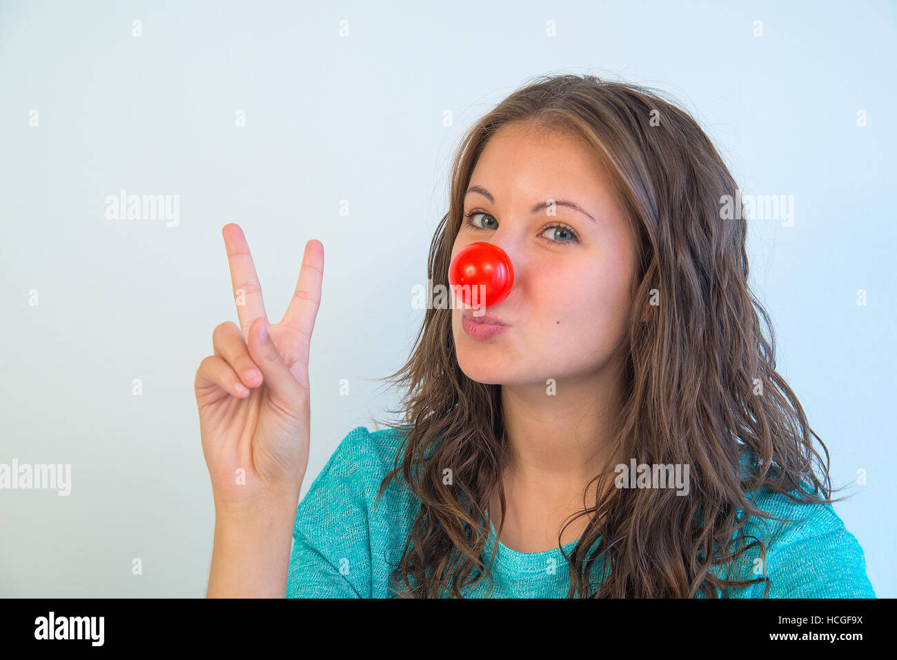 Portrait of young woman wearing clown nose and expressing victory ...