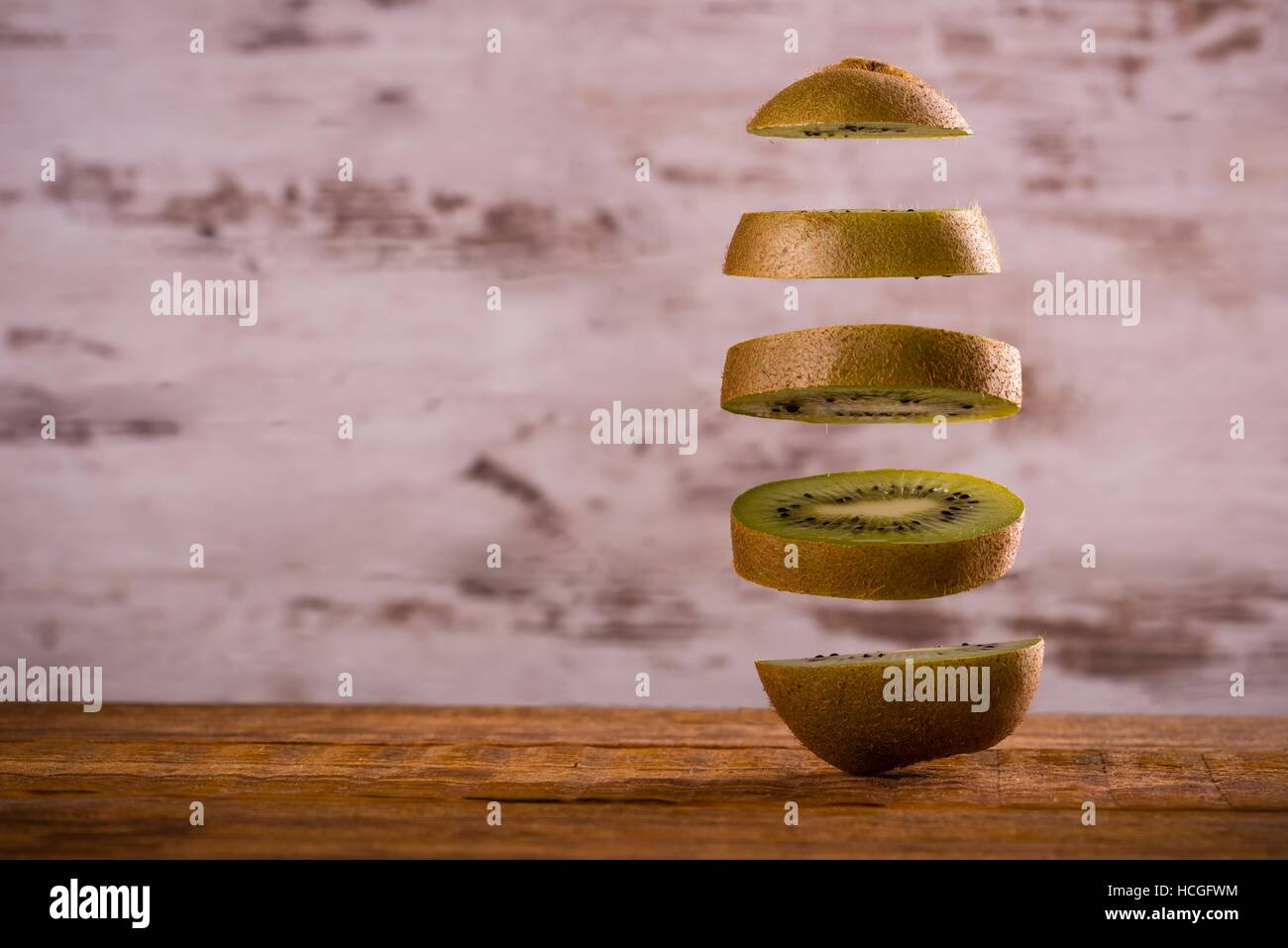 Horizontal photo of green kiwi fruit. Fruit is cut to five slices which ...