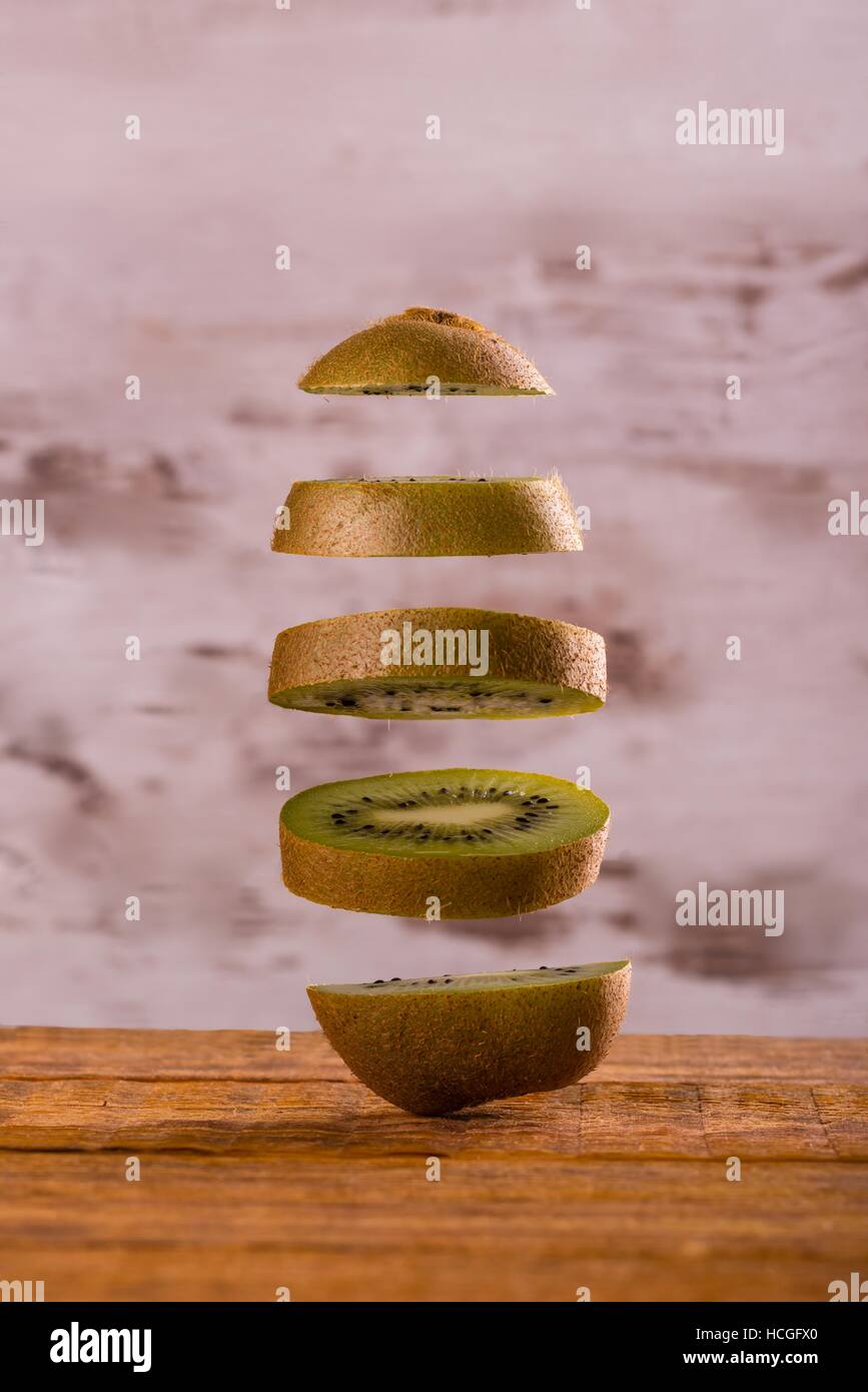 Vertical photo of green kiwi fruit. Fruit is cut to five slices which ...