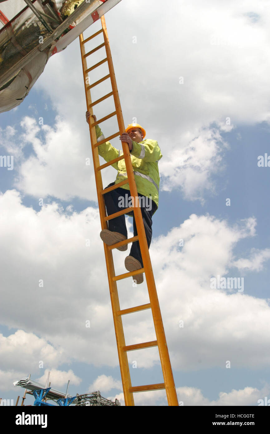 A construction worker climbs a long timber pole ladder. Photographed ...