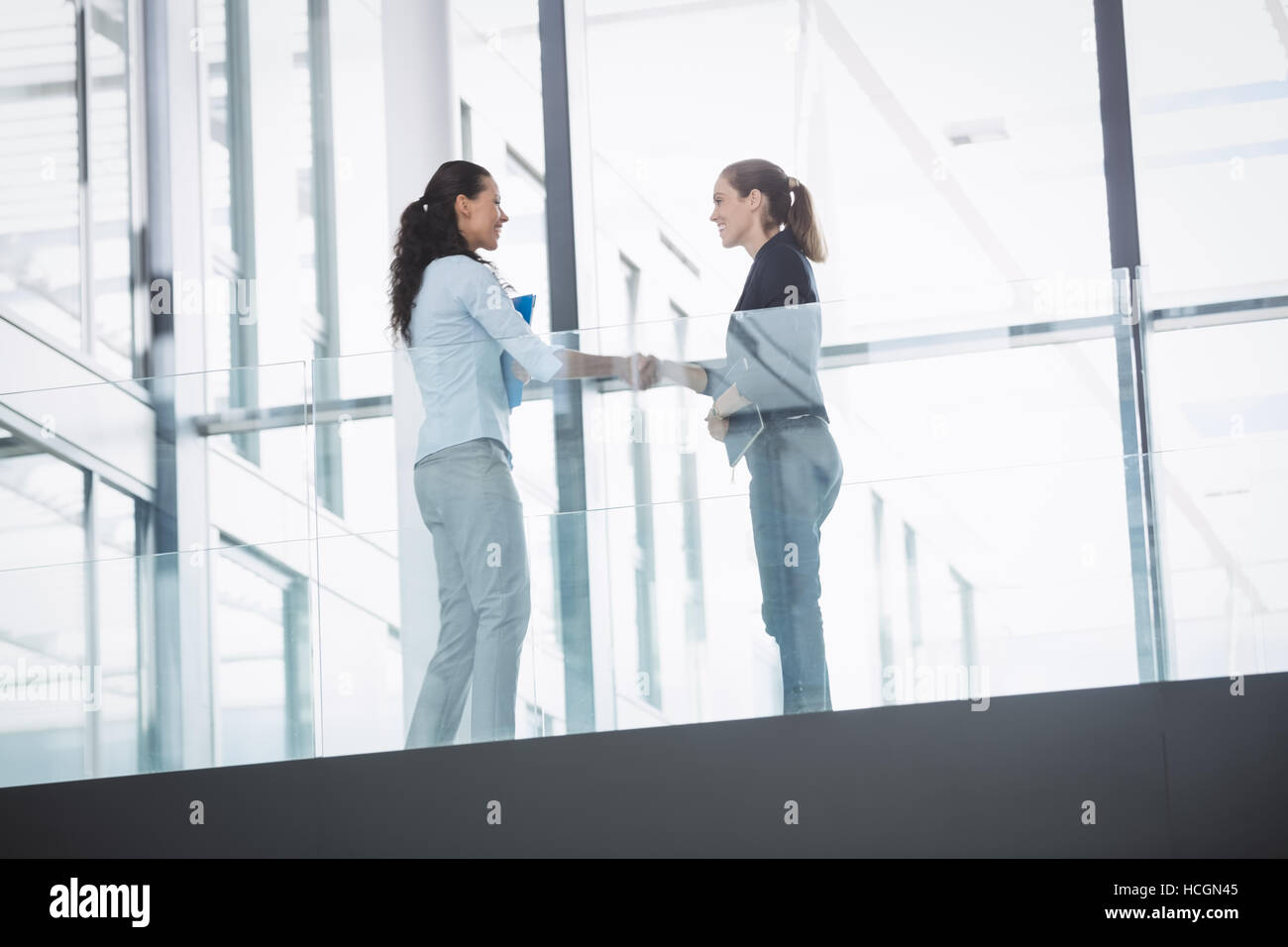 Businesswoman greeting a colleague inside office building Stock Photo ...