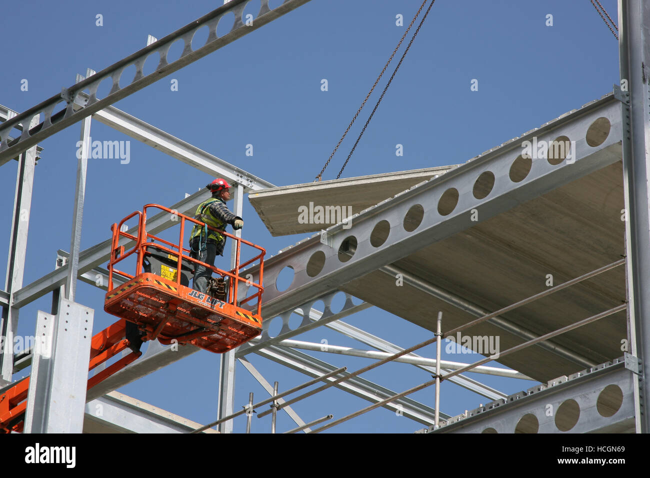PPE equipped construction worker in cherry picker fitting PCC precast ...