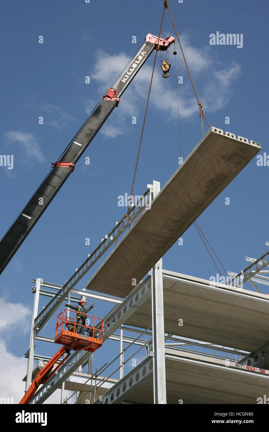 PPE equipped construction worker in cherry picker fitting PCC precast ...