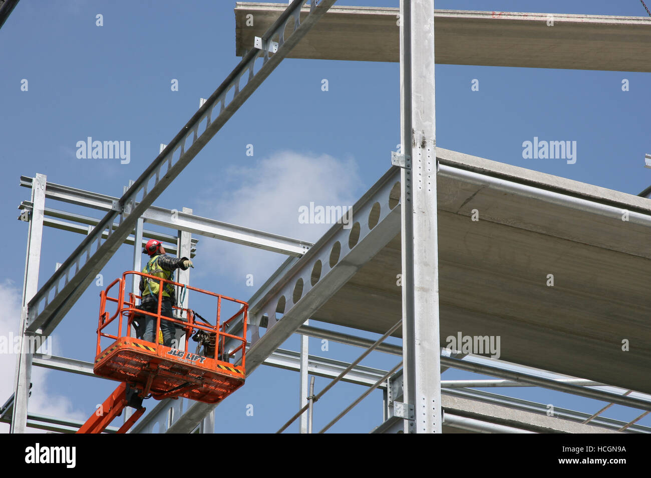PPE equipped construction worker in cherry picker fitting PCC precast ...