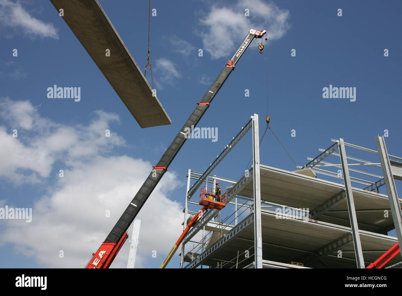 PPE equipped construction worker in cherry picker fitting PCC precast ...