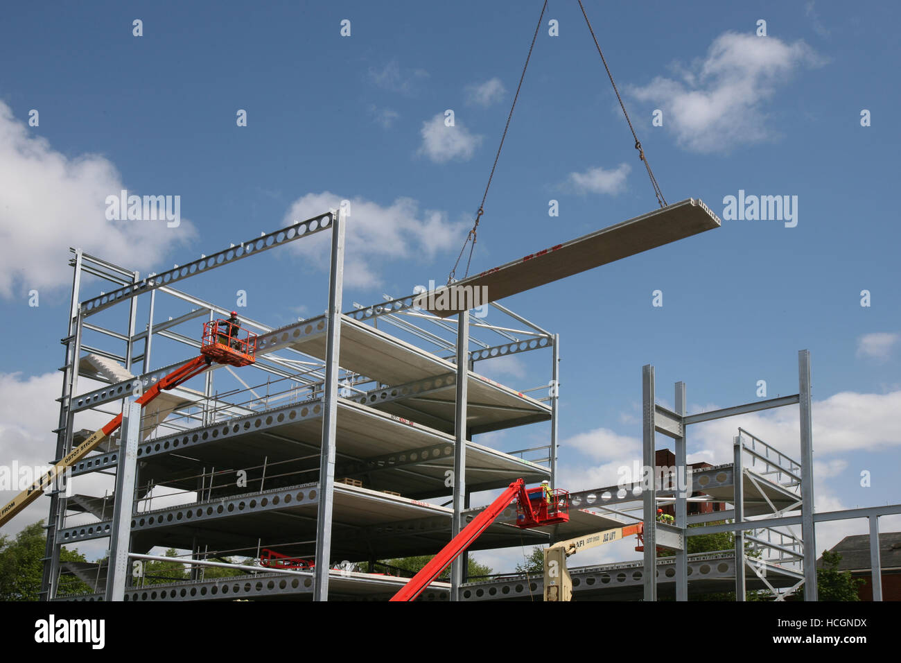 PPE equipped construction worker in cherry picker fitting PCC precast ...