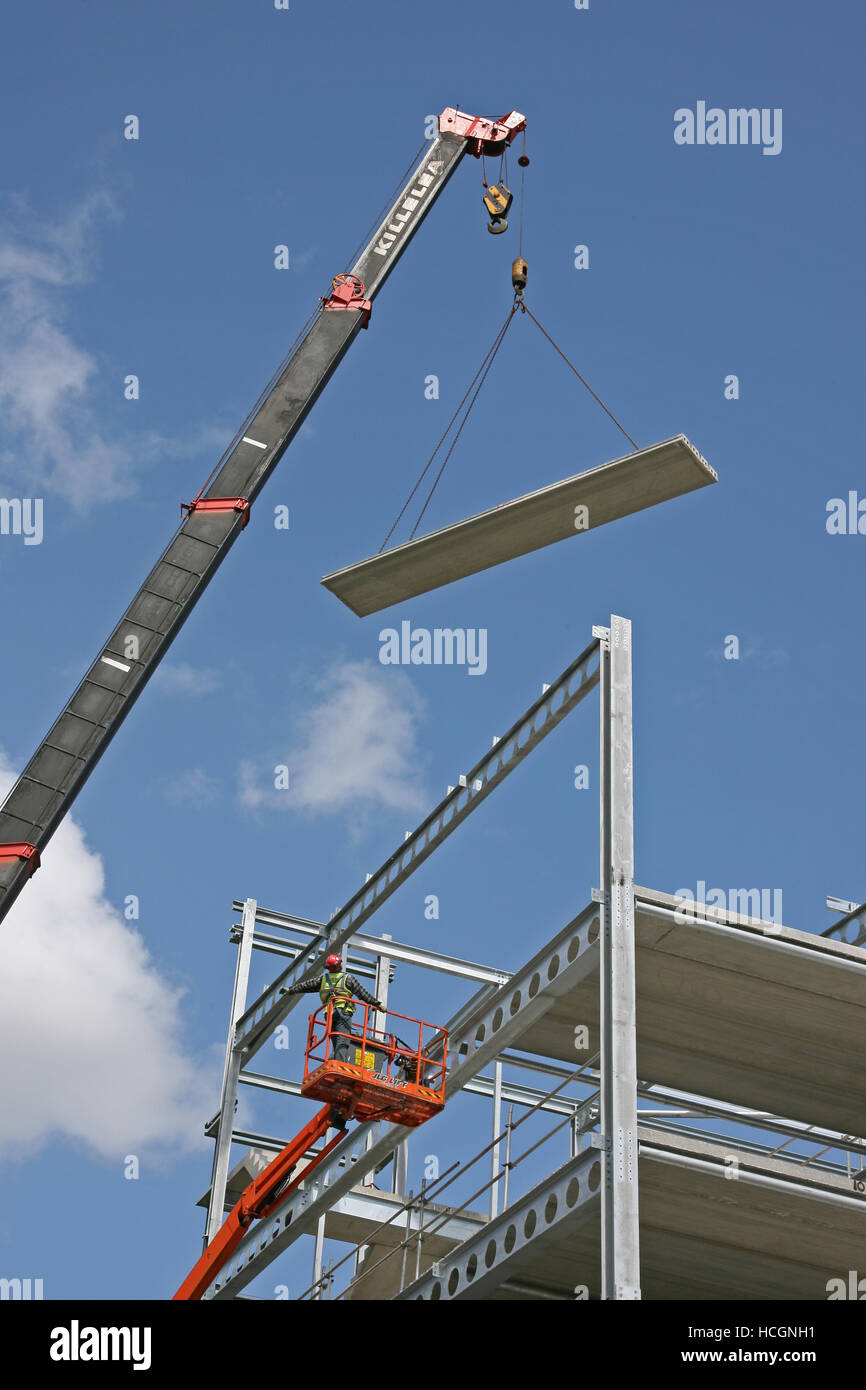 PPE equipped construction worker in cherry picker fitting PCC precast ...