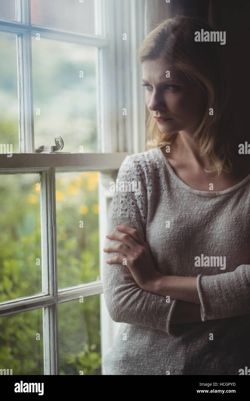 Thoughtful woman standing at window Stock Photo - Alamy