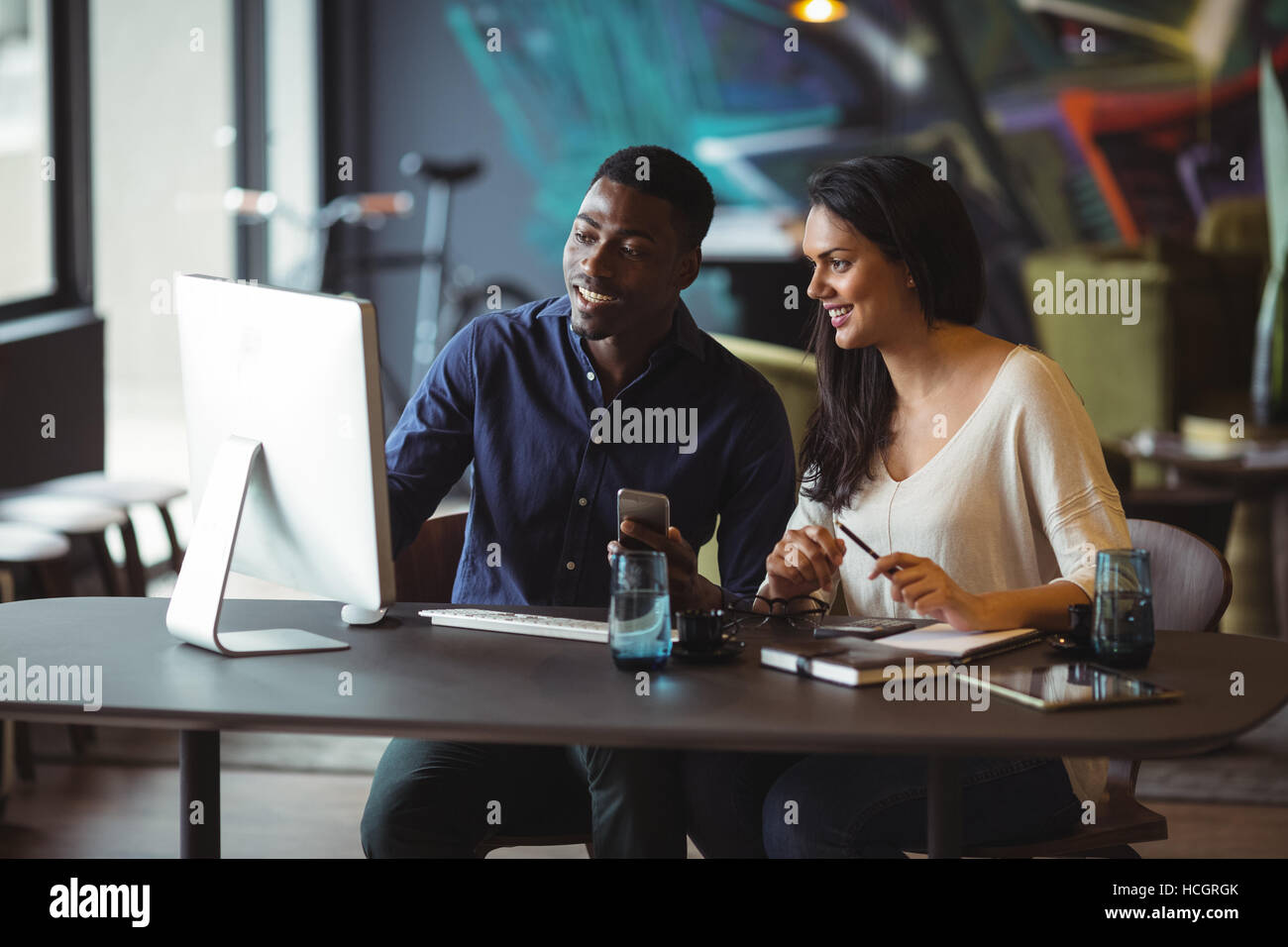 Businessman and a colleague discussing over computer Stock Photo - Alamy