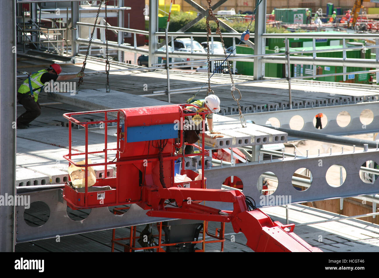 PPE equipped construction worker in cherry picker fitting PCC precast ...