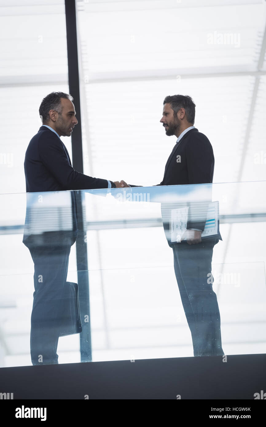 Businessman greeting a colleague inside office building Stock Photo - Alamy