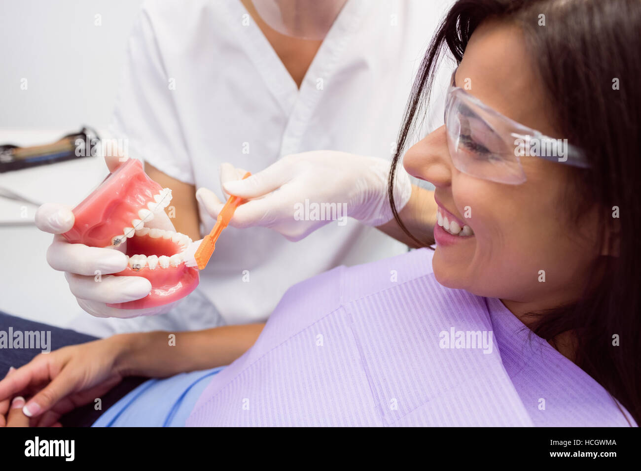 Dentist showing model teeth to female patient Stock Photo - Alamy