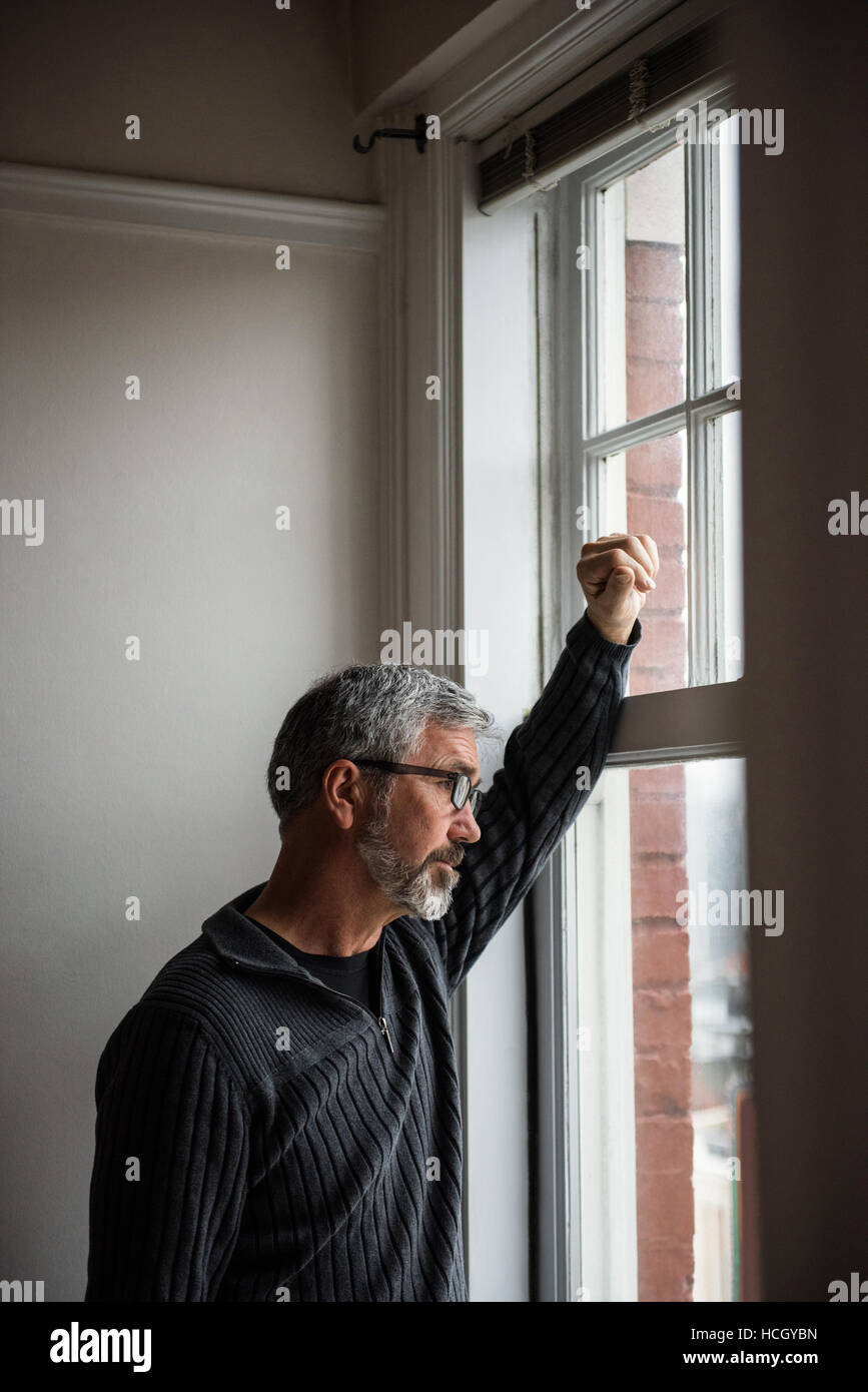 Thoughtful man looking through window Stock Photo - Alamy