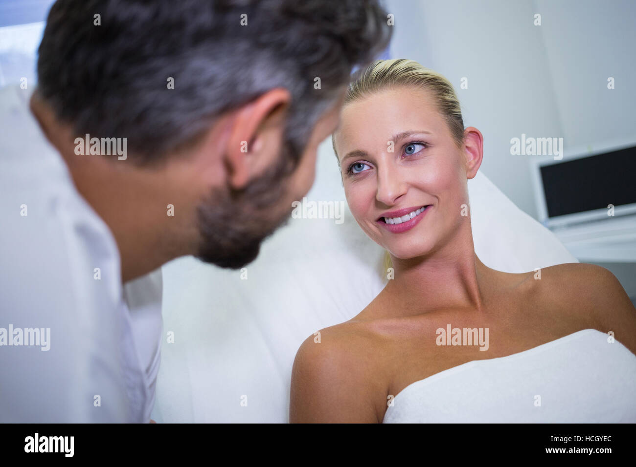 Female patient smiling while looking at doctor Stock Photo - Alamy