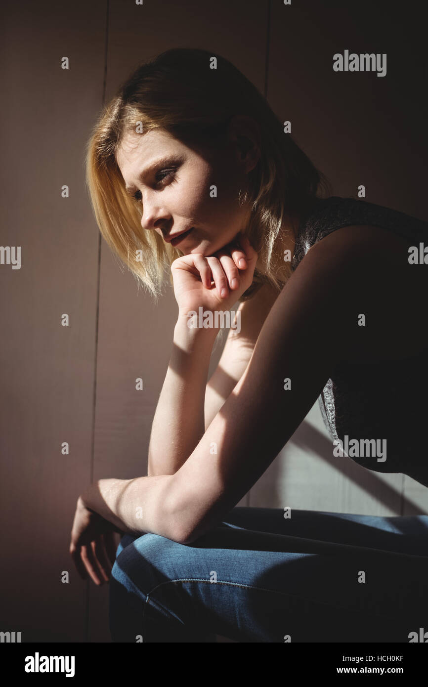 Thoughtful woman sitting with hand on chin Stock Photo - Alamy