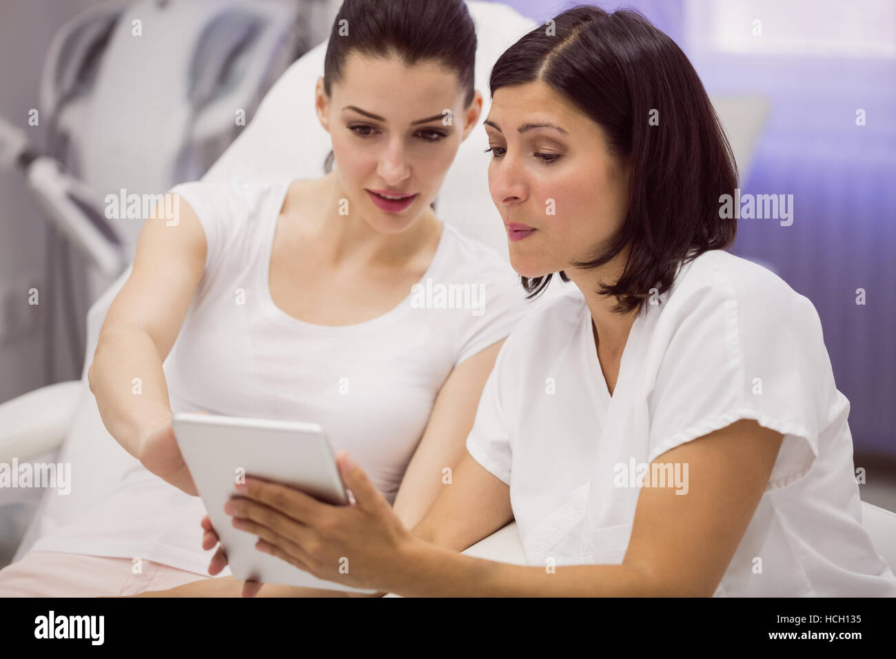Female doctor using digital tablet to consult patient Stock Photo - Alamy