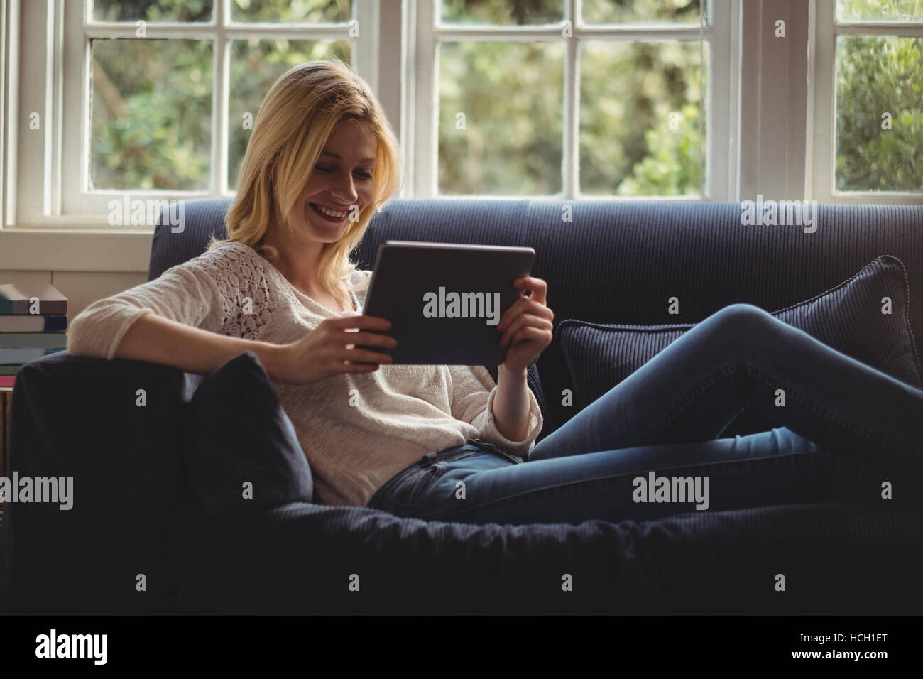 Beautiful woman sitting on sofa with digital table in living room Stock ...