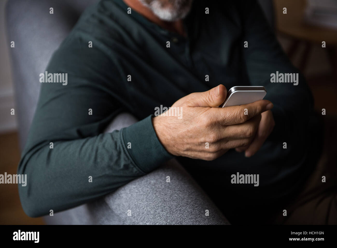 Man using mobile phone in living room at home Stock Photo - Alamy