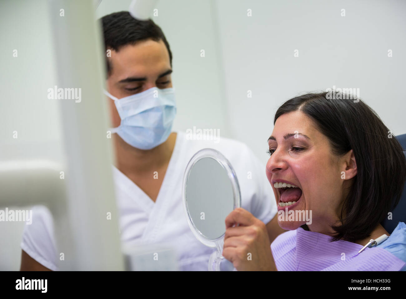 Dentist holding mirror in front of patient Stock Photo - Alamy